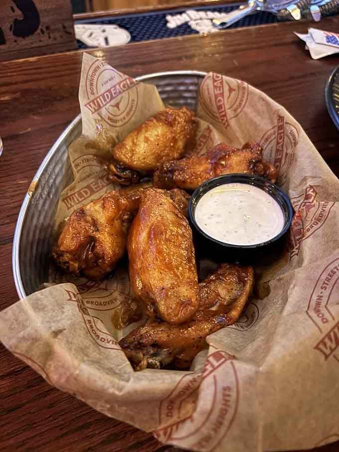 Golden-brown wings nestled in branded paper, glistening with sauce and served with ranch for the ultimate game-day experience.