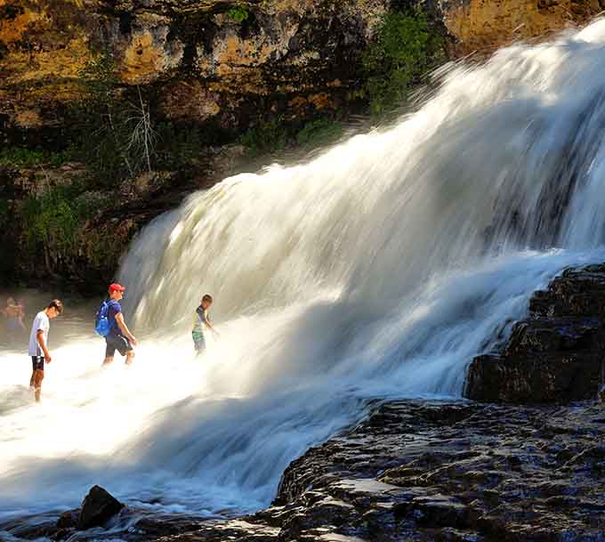 Golden hour transforms the rushing water into liquid sunshine while visitors stand mesmerized by the spectacle.
