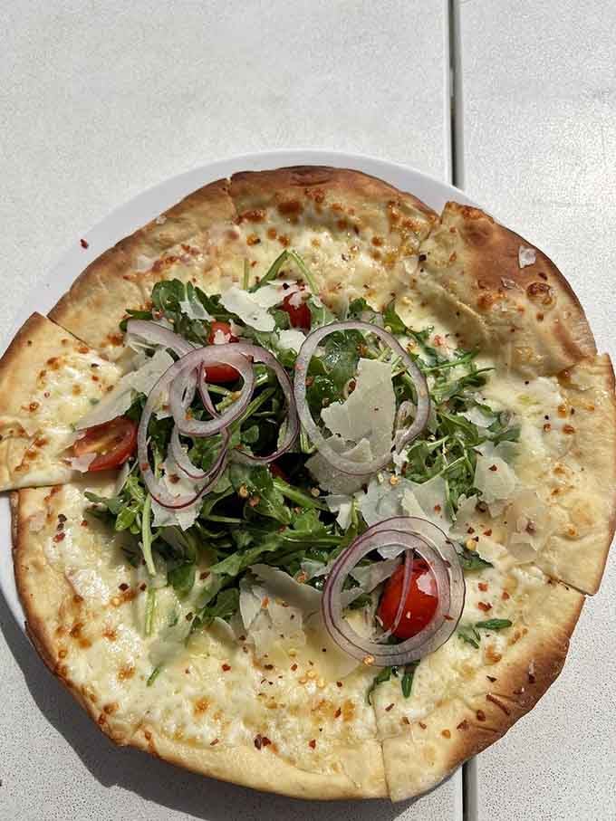 Arugula pizza topped with fresh vegetables and red onions, because sometimes sophistication comes on flatbread.