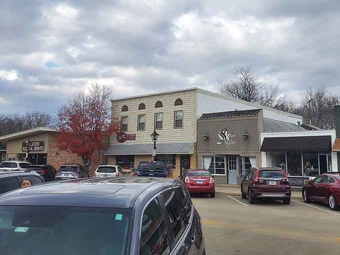 Autumn's red tree blazes against storefronts like nature's way of saying even small towns deserve dramatic seasonal displays.