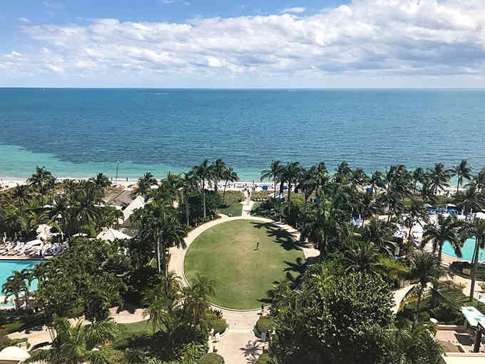 Palm trees dot a resort landscape that looks like someone's dream of paradise came to life, complete with ocean views.