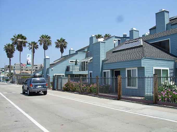 Beach houses painted in soft blues and greens nestle together, whispering secrets about the ocean just beyond.
