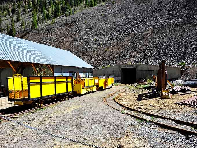 That concrete portal marked "Old Hundred" is your gateway to adventure, where bright yellow mine cars await their next passengers.