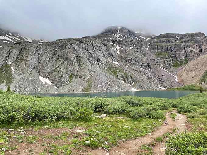 Cathedral Lake emerges from the mist like a secret revealed, its still waters reflecting centuries of geological drama overhead.