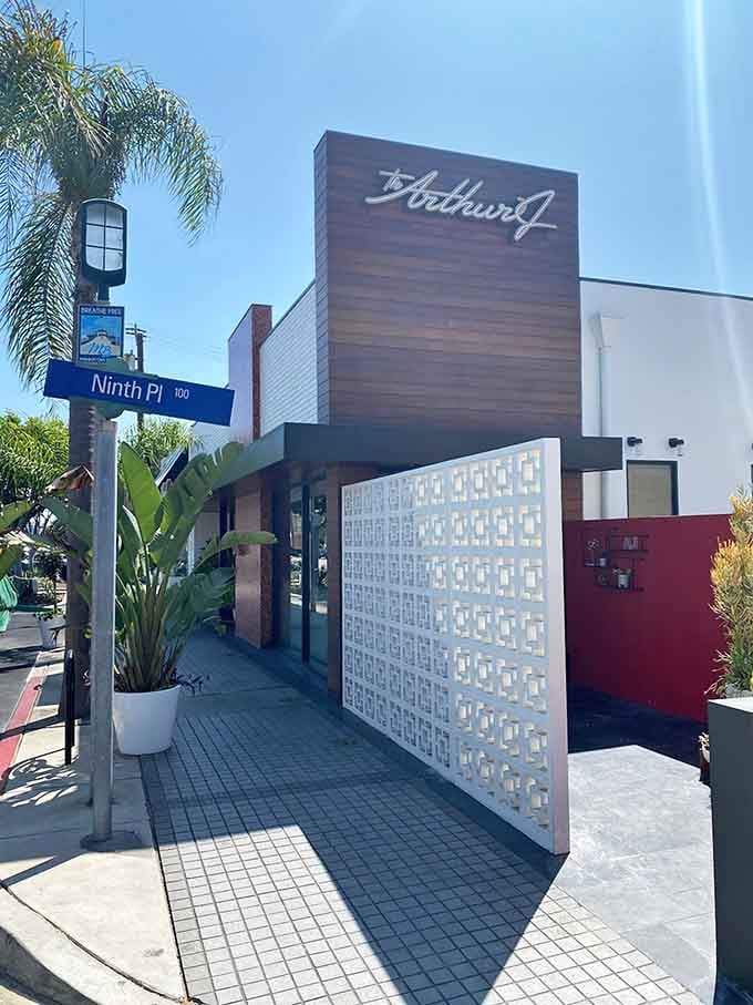 A palm tree and geometric screens frame the entrance like California decided to dress up a classic steakhouse in beachwear.