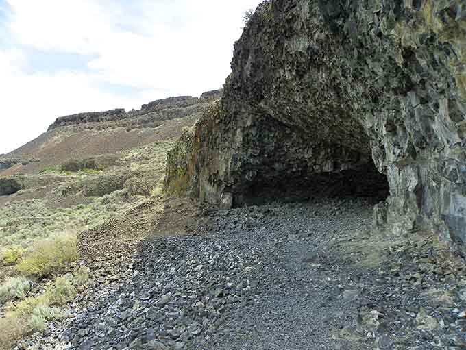 The cave entrance beckons like nature's own cathedral, carved by ancient floods into this dramatic basalt cliff.