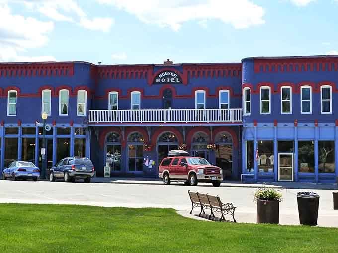 That blue building isn't just photogenic, it's practically begging you to park that bench, grab a coffee, and watch small-town life unfold.