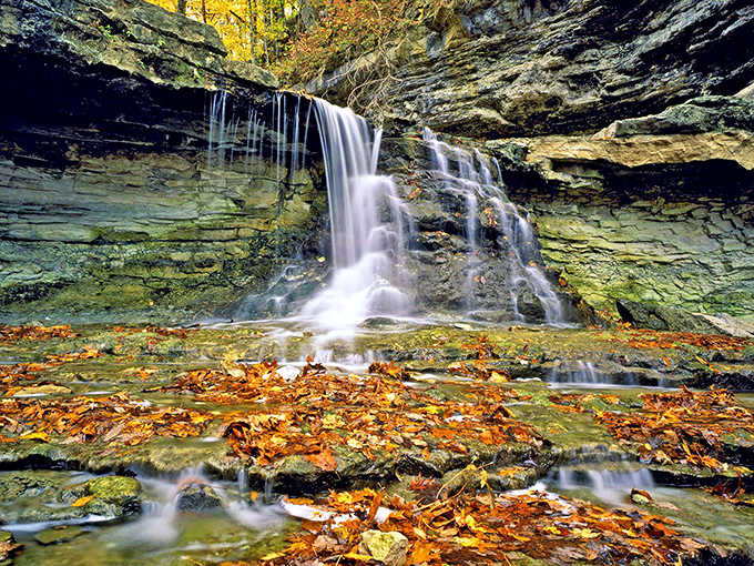 Nature's own theater puts on its best show where limestone meets waterfall in autumn's golden hour.