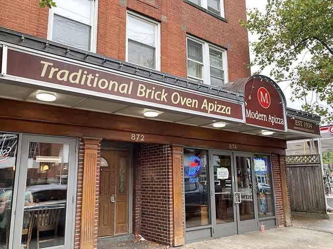 The "Traditional Brick Oven Apizza" sign isn't just advertising; it's a promise they've kept since the Depression era.