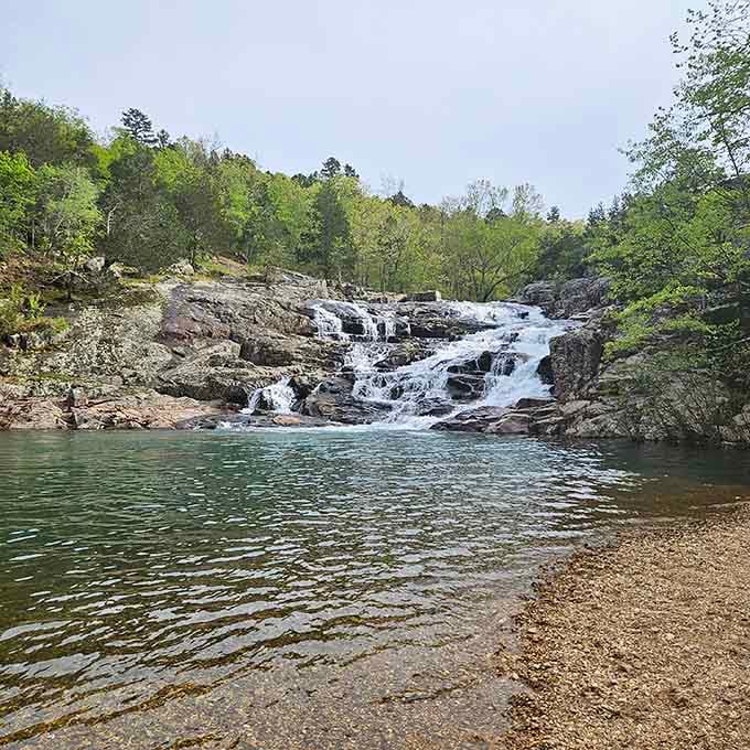 The crystal-clear swimming pool at Rocky Falls invites you to take a refreshing dip beneath the cascading waterfall above.