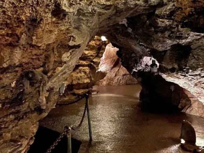 The underground stream flows peacefully through illuminated passages, showcasing the natural beauty that carved these caverns over millions of years.