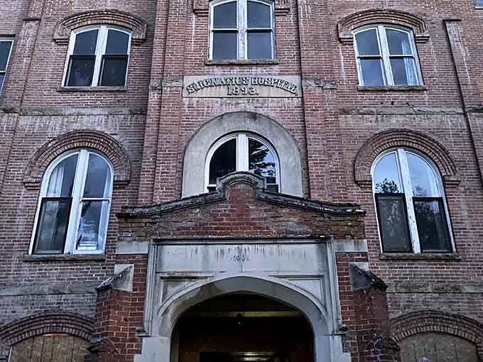 The weathered entrance still bears its name, a fading reminder of when these doors welcomed patients instead of ghost hunters.