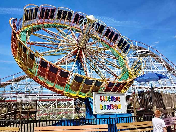The Electric Rainbow spins bright against wooden coaster frames, proving old-school amusement parks still know how to party.