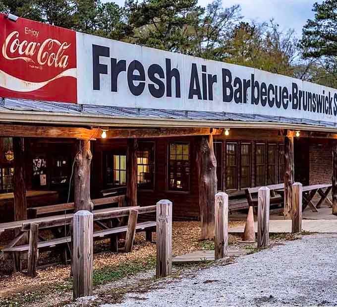 Rustic wooden posts and picnic-style seating create an authentic barbecue atmosphere where generations of families have gathered to enjoy legendary smoked meats together.