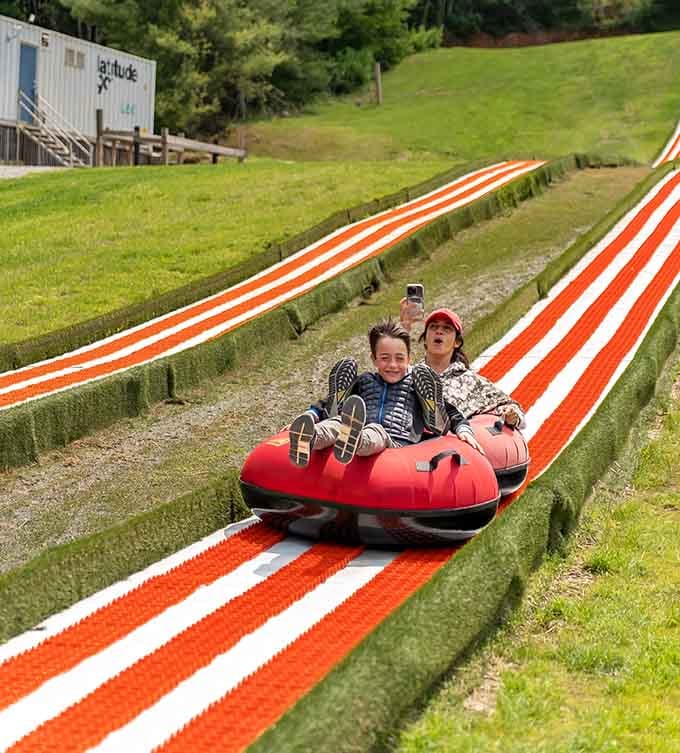 Two tubers sharing a ride down those vibrant orange and white lanes, pure joy captured mid-descent.