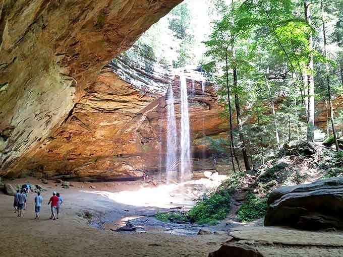 The waterfall cascades like liquid silk over ancient sandstone, proving Mother Nature never needs a special effects budget.