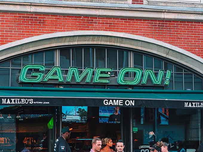The inviting entrance to Game On! welcomes sports fans with its bright neon signage and prime location near Fenway Park.