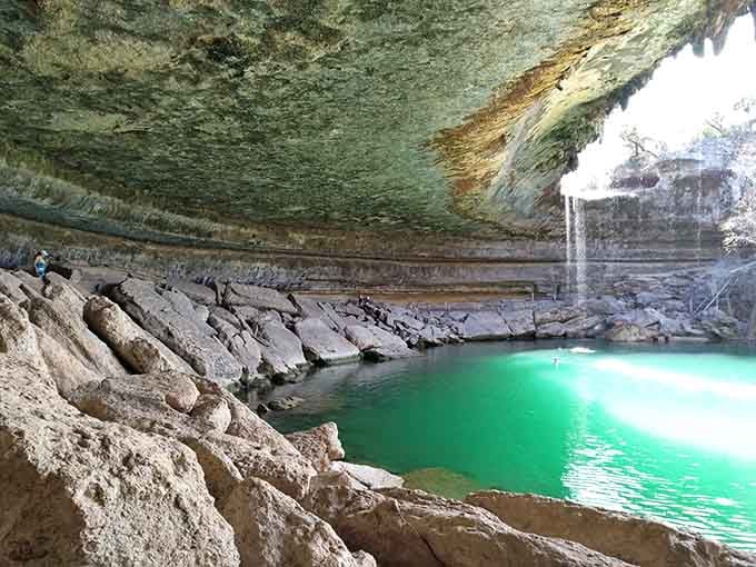 Stalactites dripping overhead while jade-green water beckons below creates the ultimate natural cathedral worth every reservation hassle.