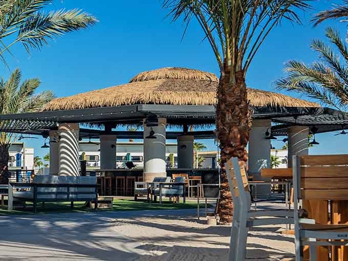 The thatched-roof tiki bar surrounded by palms brings authentic tropical vibes to the Arizona desert in style.