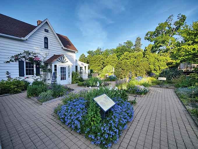 Winding brick paths lead you through vibrant garden beds where blue blooms steal the show against the charming white buildings.