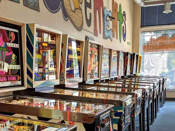 Natural light streams through the window, illuminating rows of pinball perfection like a museum dedicated to fun.