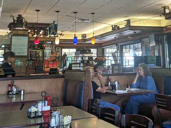 Classic diner booths meet superhero memorabilia in this cozy dining room where Batman watches from shelves while you enjoy your meal.