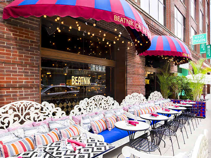 Colorful awnings and patterned cushions turn sidewalk seating into a bohemian dream where every meal feels like a celebration.