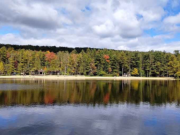Fall's early whispers paint the shoreline while mirror-perfect water reflects every tree like nature's own Polaroid snapshot.