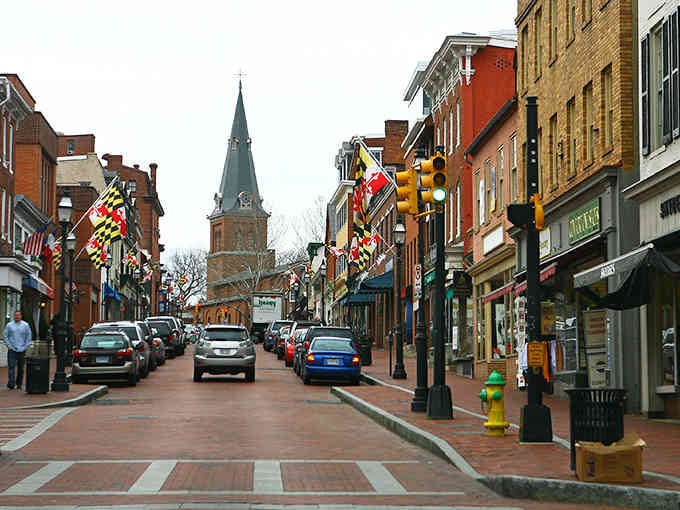 Downtown Annapolis showcases its charming brick streets and colorful colonial buildings, with Maryland flags proudly displayed throughout the historic shopping district.