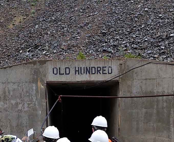 That concrete portal marked "Old Hundred" is your gateway to adventure, where bright yellow mine cars await their next passengers.