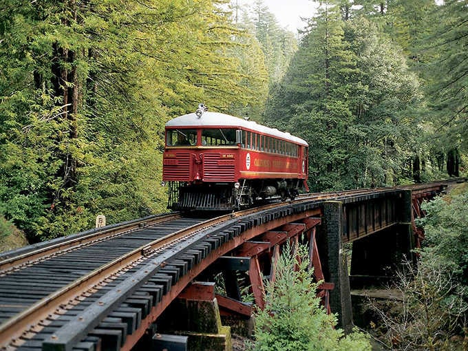 That classic red railcar crossing a forest trestle is your ticket to California's most cinematic train ride.