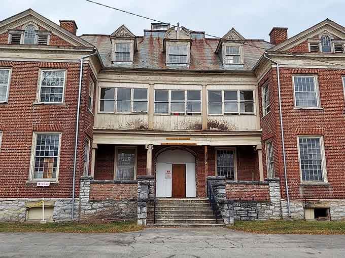 The main entrance stands weathered but dignified, like it's still trying to maintain some semblance of institutional authority.