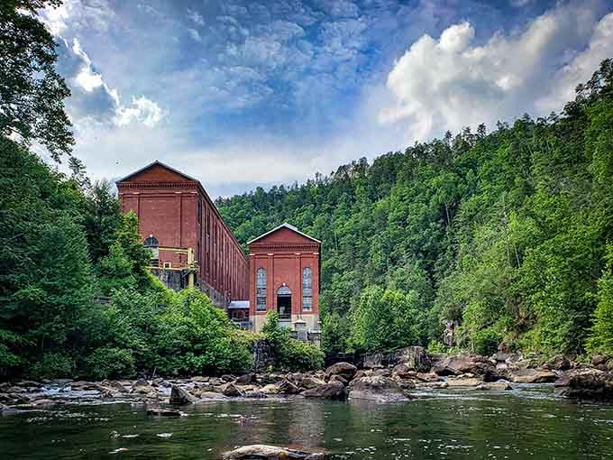 That historic red brick powerhouse rising from the forest looks like something from a vintage postcard come to life.