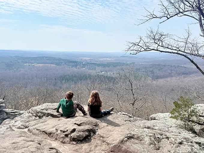 Two friends perched on ancient sandstone, sharing a view that stretches beyond the horizon into pure contentment.