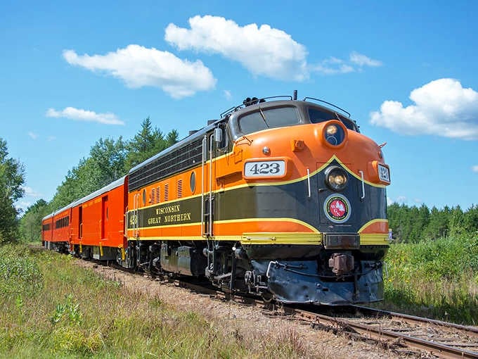 That gorgeous orange and black locomotive isn't just for show; it's your ticket to Wisconsin's wilderness wonderland.