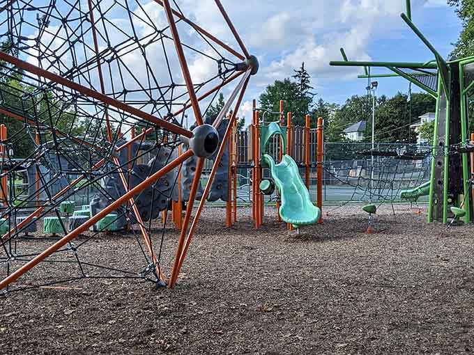 The vibrant playground sprawls beneath mature trees, creating that perfect blend of adventure and natural shade every parent dreams about.