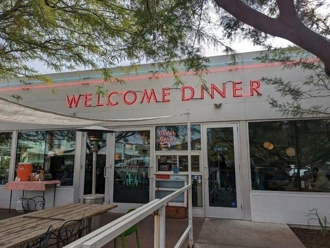 Framed by desert trees and glowing signage, this entrance promises good times and even better food ahead.