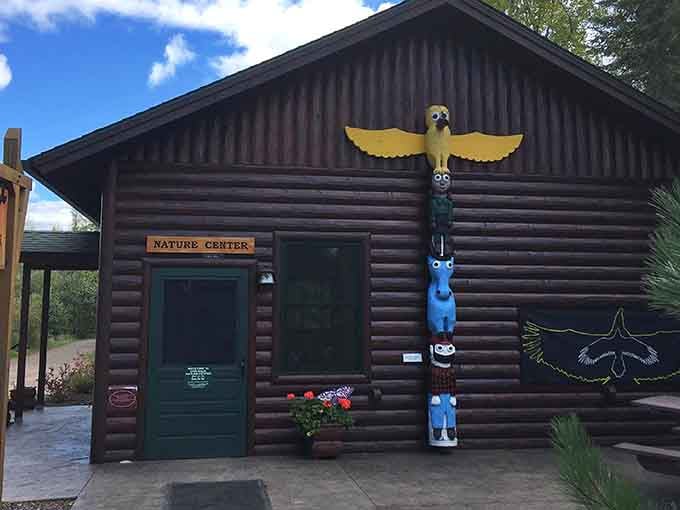 Traditional log construction and whimsical totem pole carvings create a perfect blend of natural beauty and cultural heritage at the entrance.