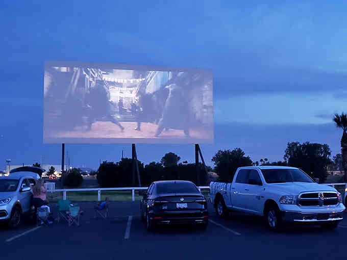 Families claim their spots in the lot, transforming ordinary parking spaces into personal theaters for the night.