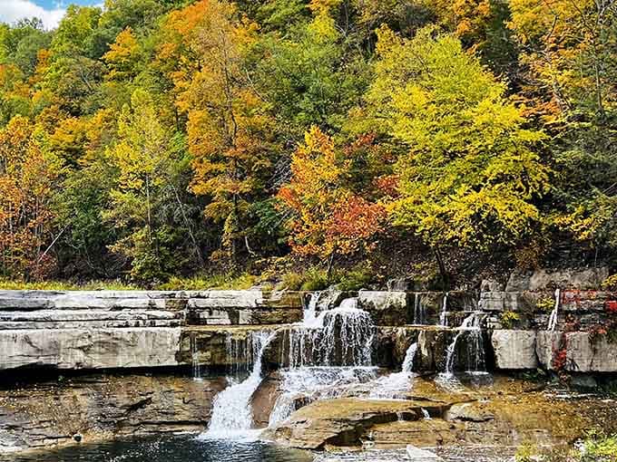 Nature's stair-step masterpiece in full autumn glory, where water dances over ancient rock like a liquid symphony.