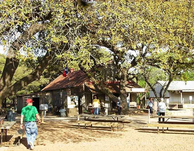 Under ancient oaks and weathered wood, this legendary Texas gathering spot proves paradise doesn't need a zip code.