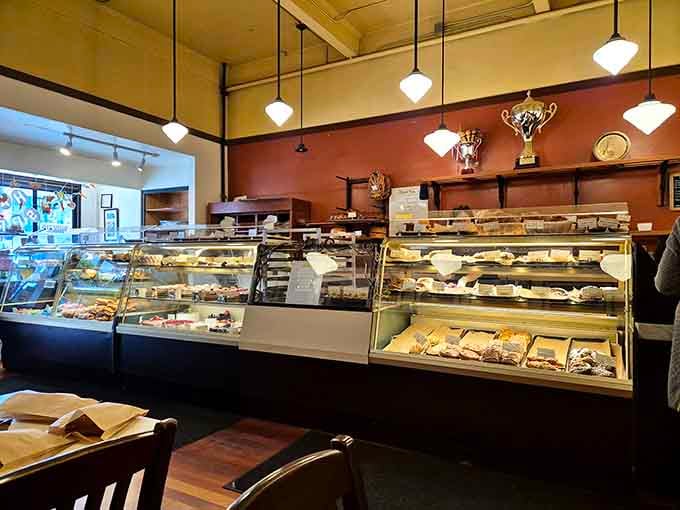The glass case beckons like a siren song, promising buttery treasures that'll derail your diet before noon.