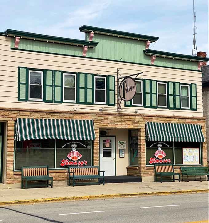 Classic striped awnings frame this storefront like it's straight out of a simpler time when everything moved slower and tasted better.