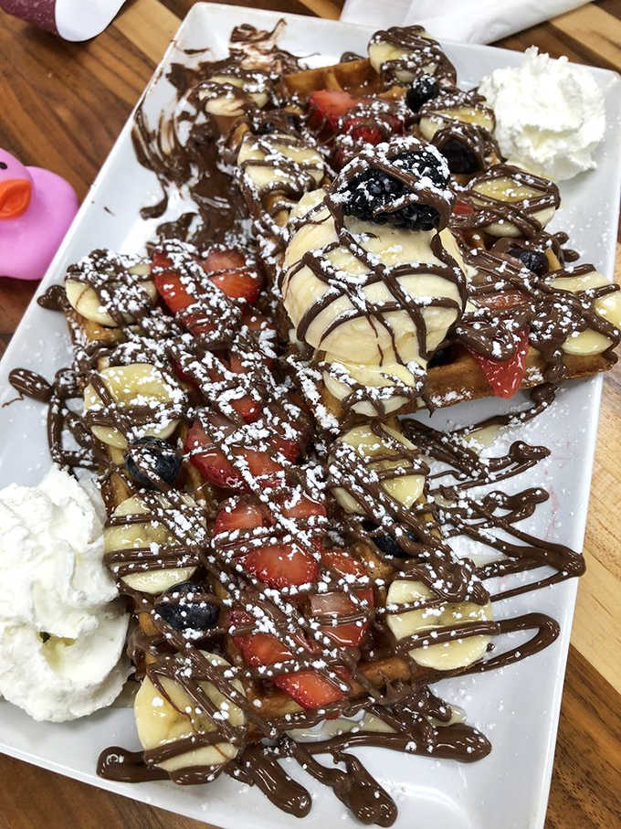 Fresh strawberries piled on a golden waffle with ice cream and chocolate, making every diet start "tomorrow."