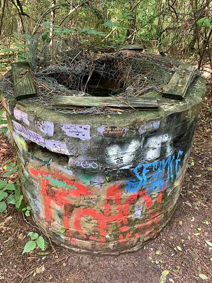This graffiti-covered brick cylinder stands as a weathered monument to the area's industrial past, now serving as an unexpected canvas.