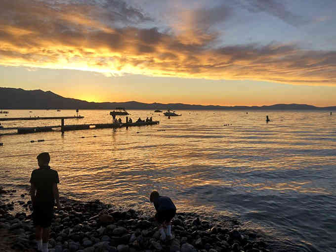 Golden skies meet silhouetted figures in a sunset that makes every beach day worth the drive.