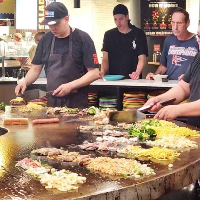 Grill masters orchestrate multiple orders simultaneously on the massive circular cooking surface with impressive precision.