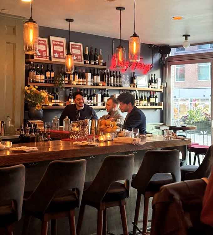 The bar glows with amber pendant lights and that unmistakable neon "Happiness" sign, setting the mood perfectly for dinner.