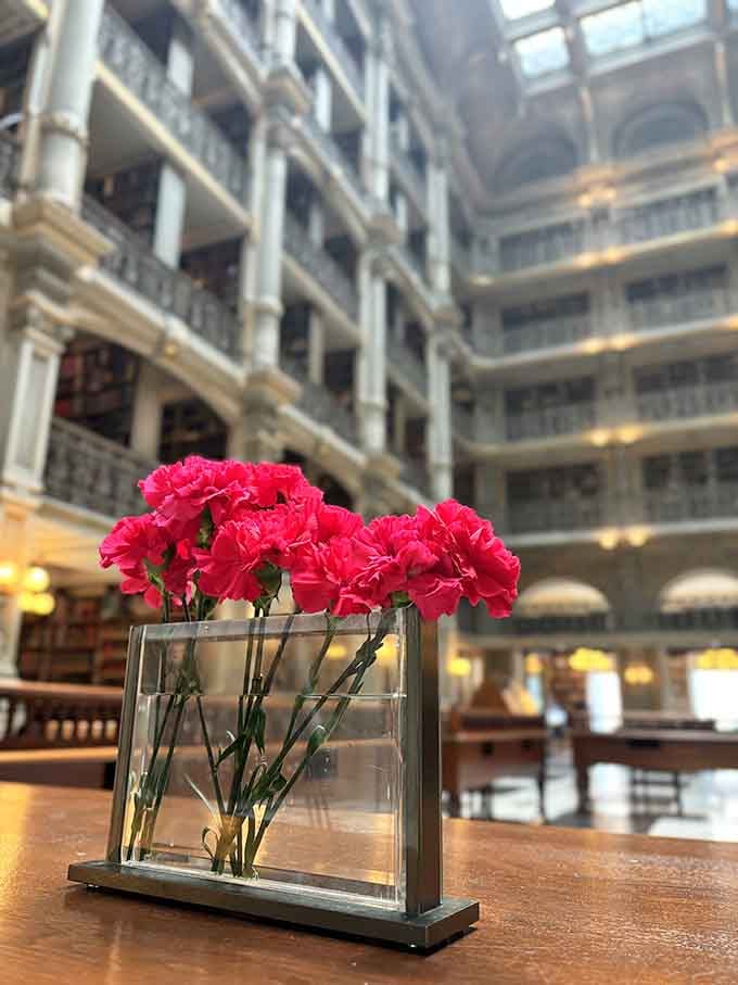 Bright carnations bring cheerful color against the soaring backdrop of five-story balconies stacked with literary treasures beyond.