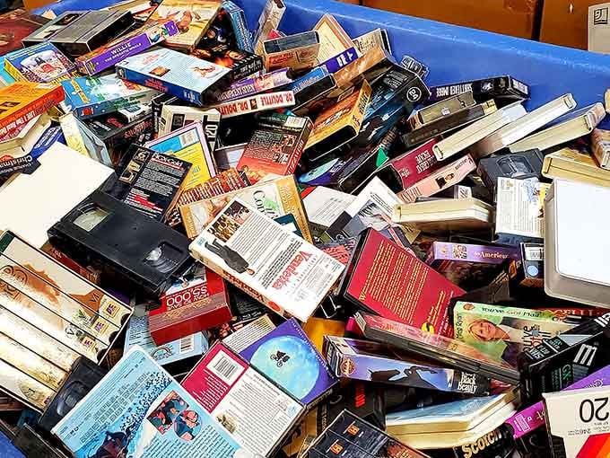 VHS tapes and DVDs pile high like a time capsule of movie nights past, ready for nostalgic rediscovery.